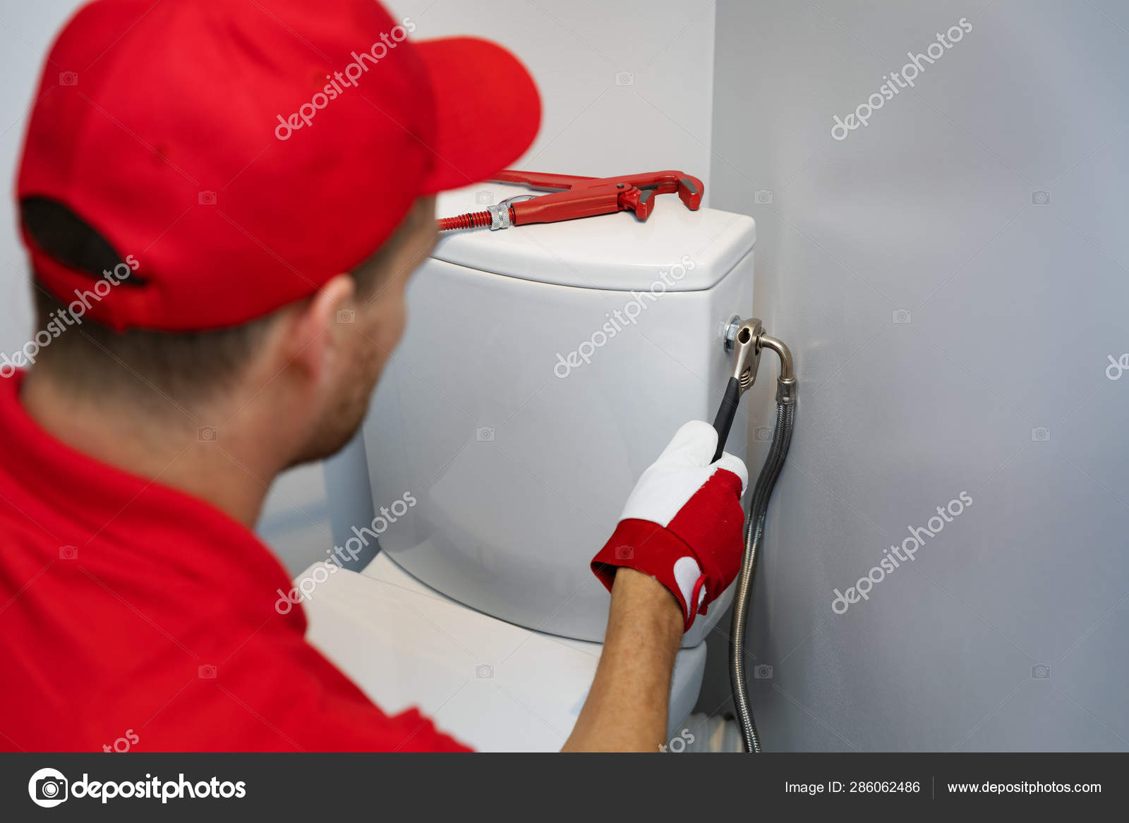 Plumber working in toilet installing flexible water pipe to wc t Stock ...