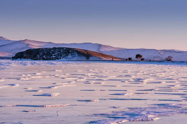 View of the ice and the rising sun over the mountains, lake Baikal ...