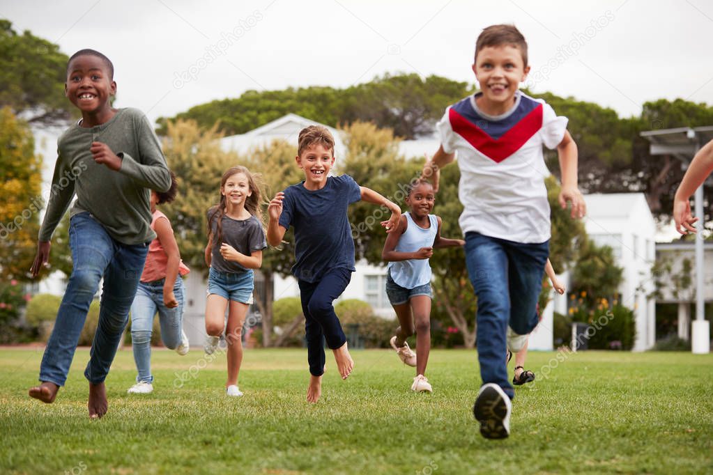 Alumnos de la escuela primaria emocionados corriendo a través del campo ...