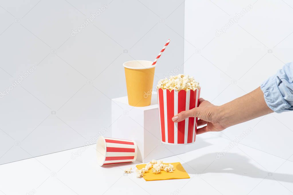 Palomitas de ma z en cubo de rayas de papel reciclable sostenido por la mujer sobre fondo blanco ...