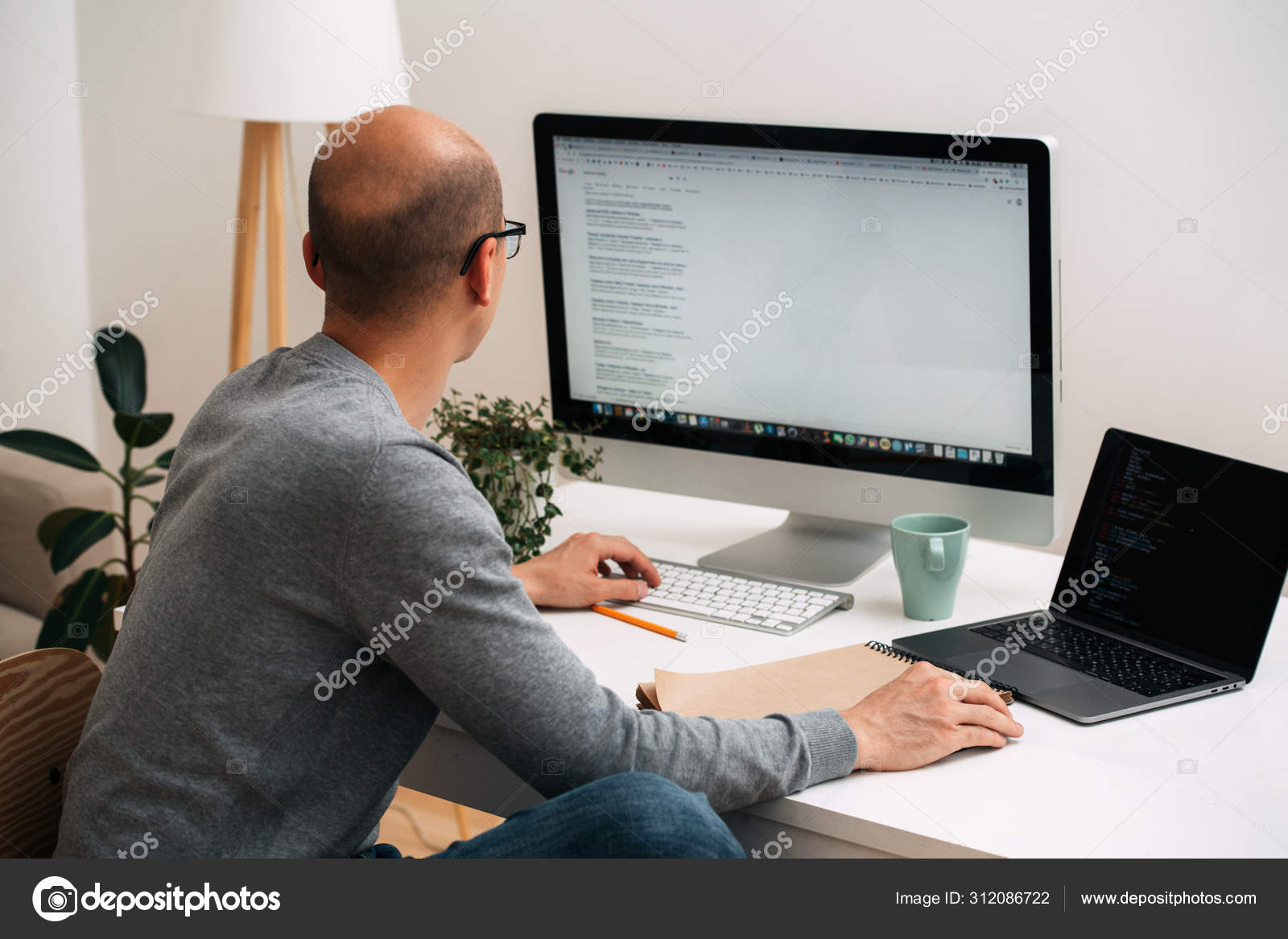 Programmer, working behind the desk, googling and coding at the same ...