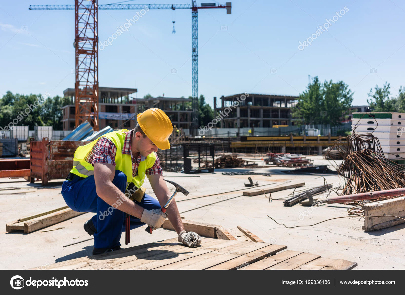 Vista lateral de un joven trabajador clavando un clavo en la madera ...