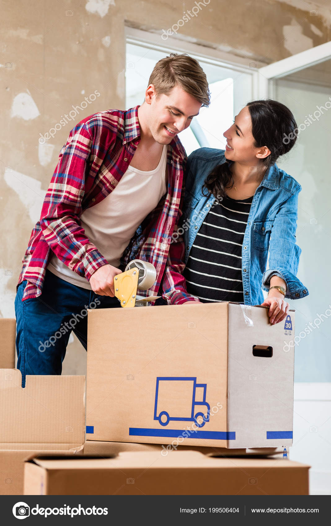 Young man and his girlfriend sealing a box while renovating their home ...