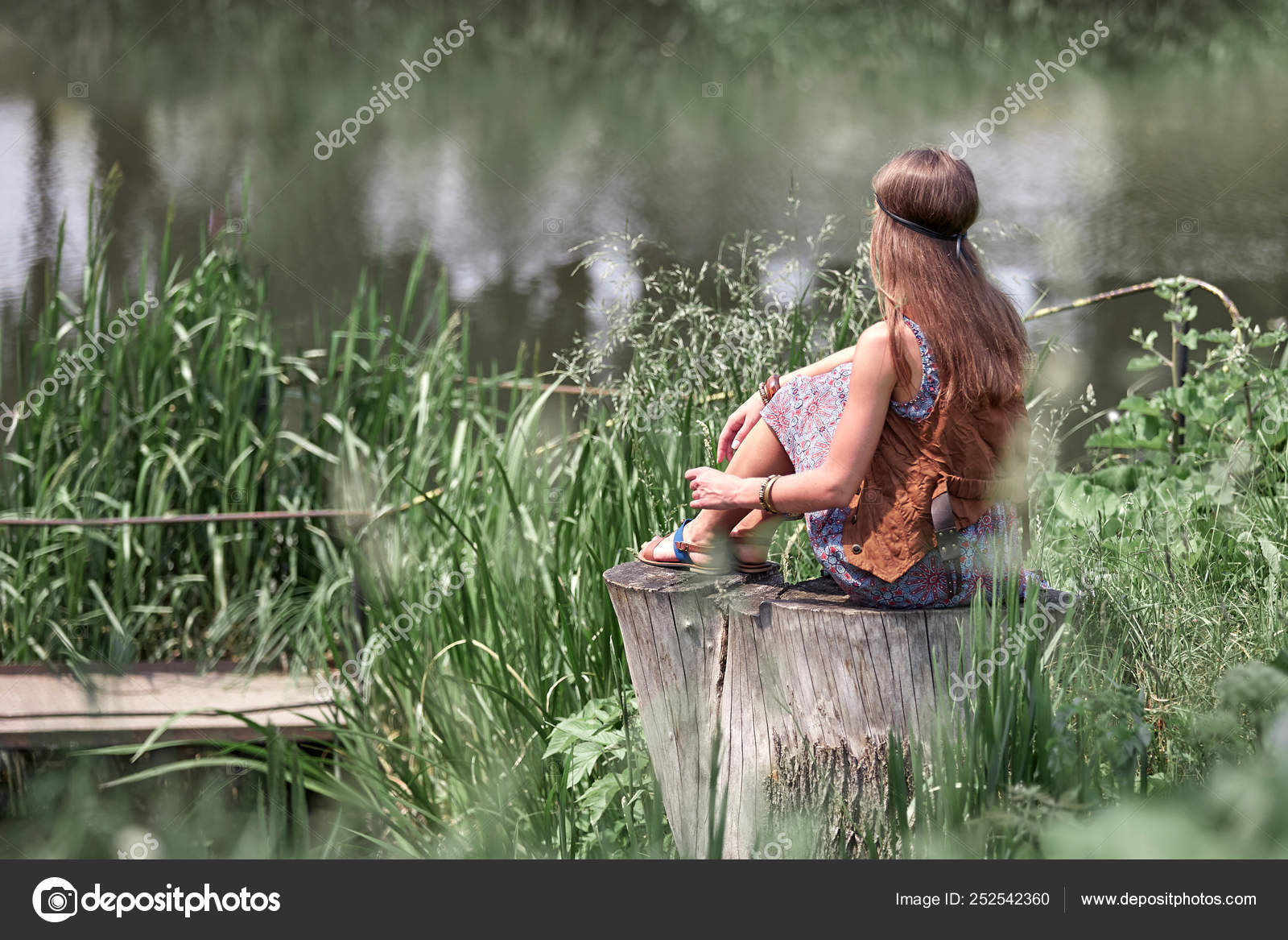 Beautiful hippie girl sitting on a stump and looking at the pond Stock Photo by ©albertyurolaits ...