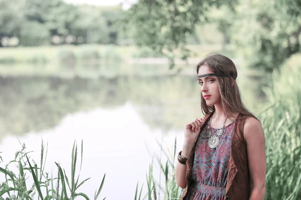 Beautiful hippie girl sitting on a stump near the pond. Stock Photo by ©albertyurolaits 269813526