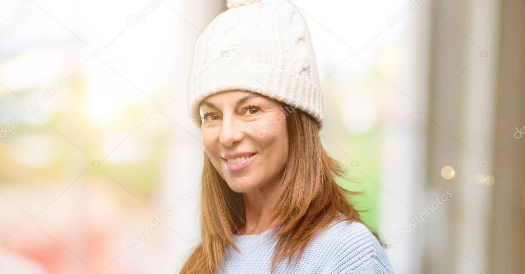 Mujer de mediana edad con gorra de invierno de lana segura y feliz con ...