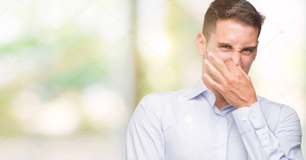 Joven hombre de negocios guapo oliendo algo apestoso y asqueroso, olor ...