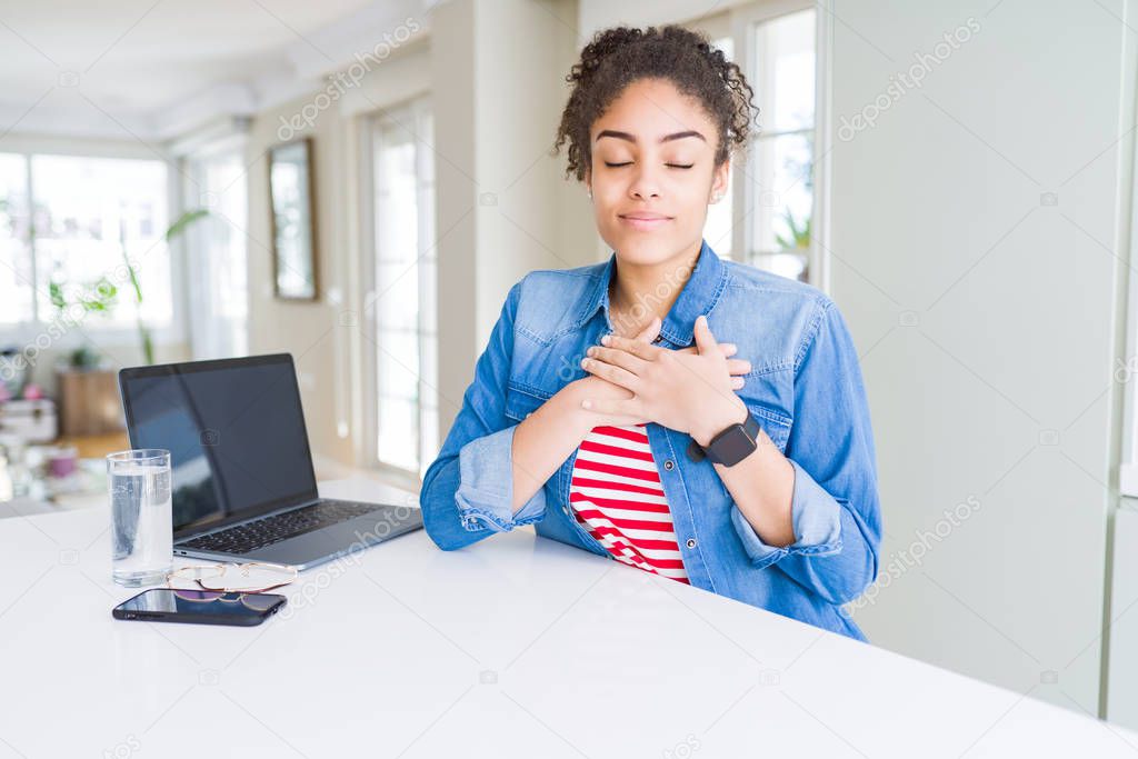 Joven mujer de negocios afroamericana que trabaja usando computadora portátil sonriendo con las ...