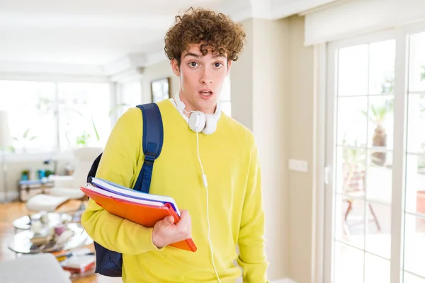 Young student man wearing headphones and backpack holding notebooks ...