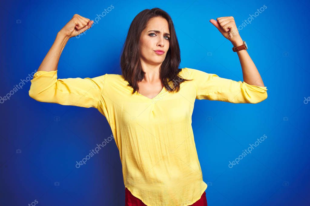 Mujer hermosa joven con camiseta amarilla de pie sobre fondo azul ...