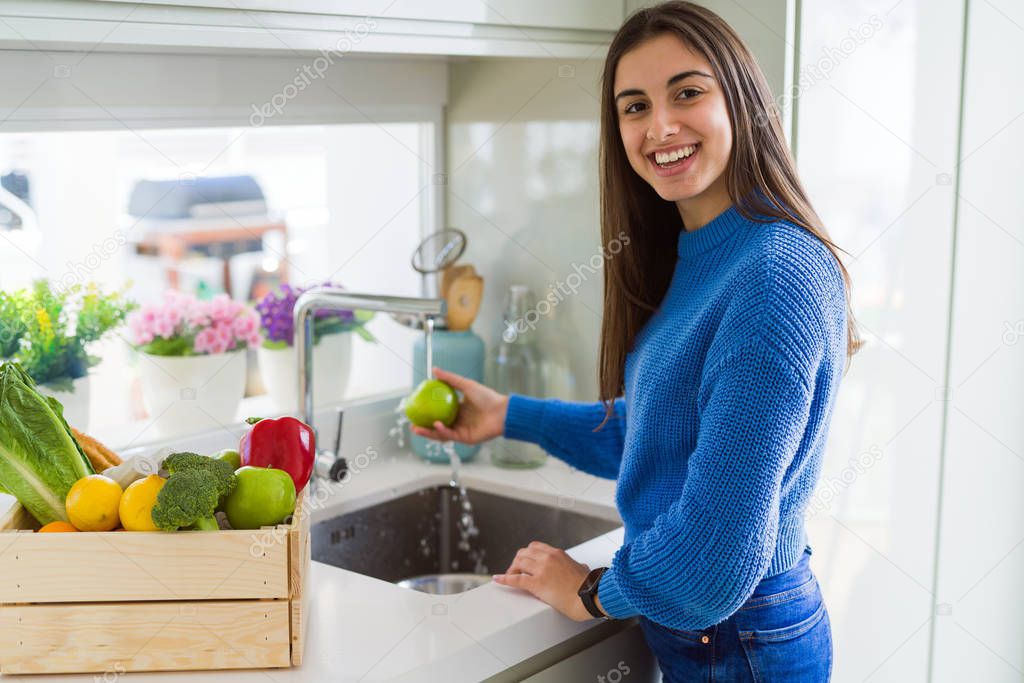 Mujer joven lavando verduras y frutas usando agua del fregadero 2023