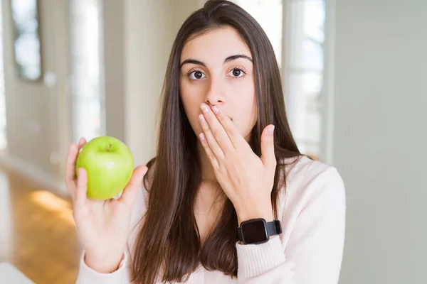 Beautiful young woman eating healthy green apple fruit cover mouth with ...
