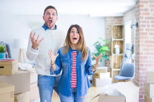 Young beautiful couple standing at new home around cardboard boxes ...