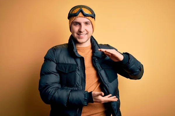 Young handsome caucasian man wearing hat, coat and ski glasses for ...