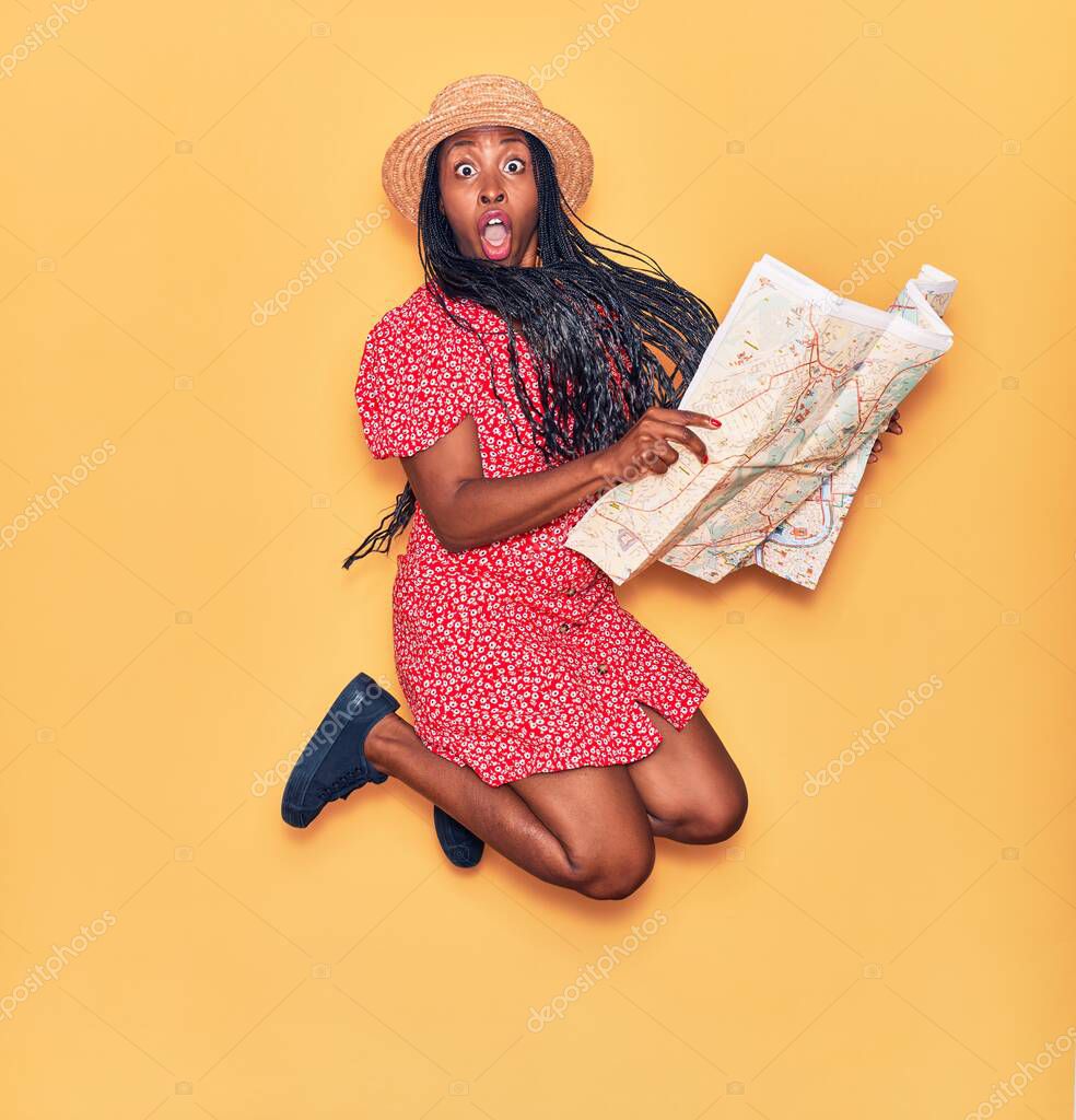 Joven hermosa mujer afroamericana sorprendida con la boca abierta con ropa de verano y sombrero ...