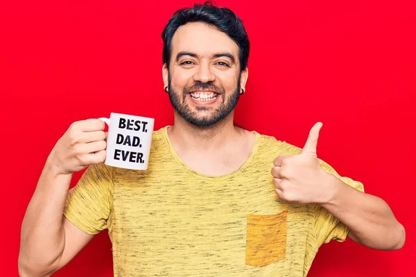 Young hispanic man drinking mug of coffe with best dad ever message ...