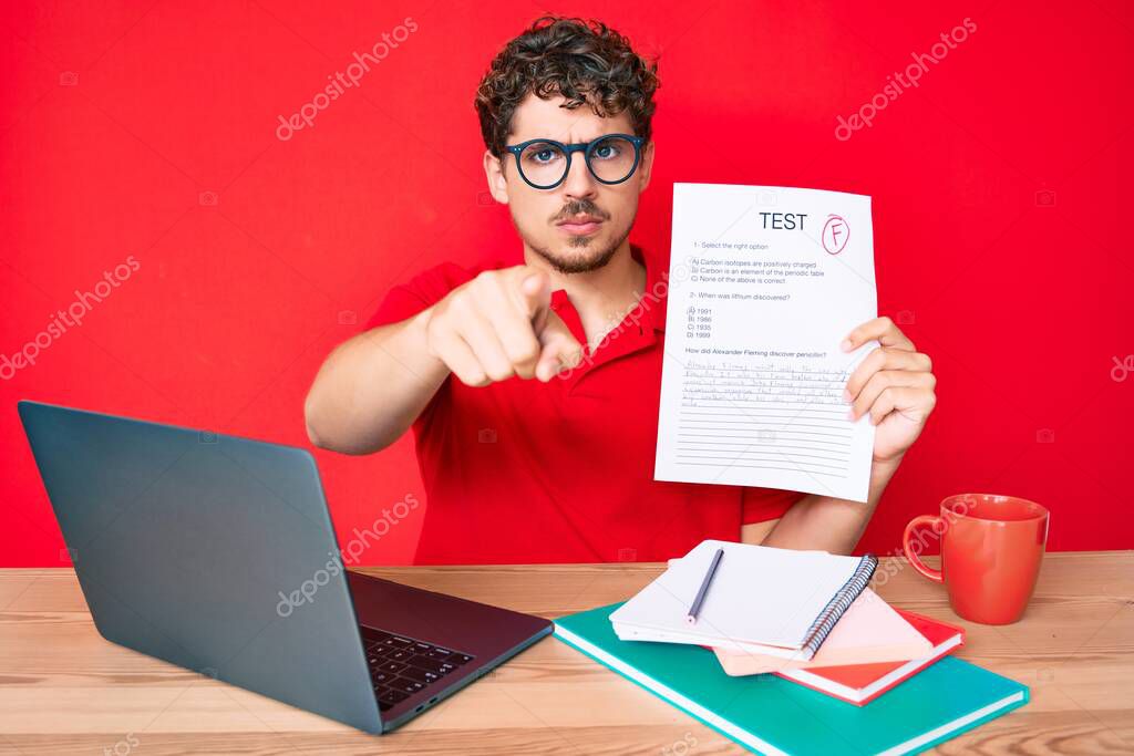 Joven hombre caucásico con el pelo rizado sentado en la mesa que ...