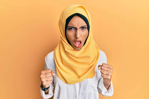 Young brunette arab woman wearing traditional islamic hijab scarf angry ...