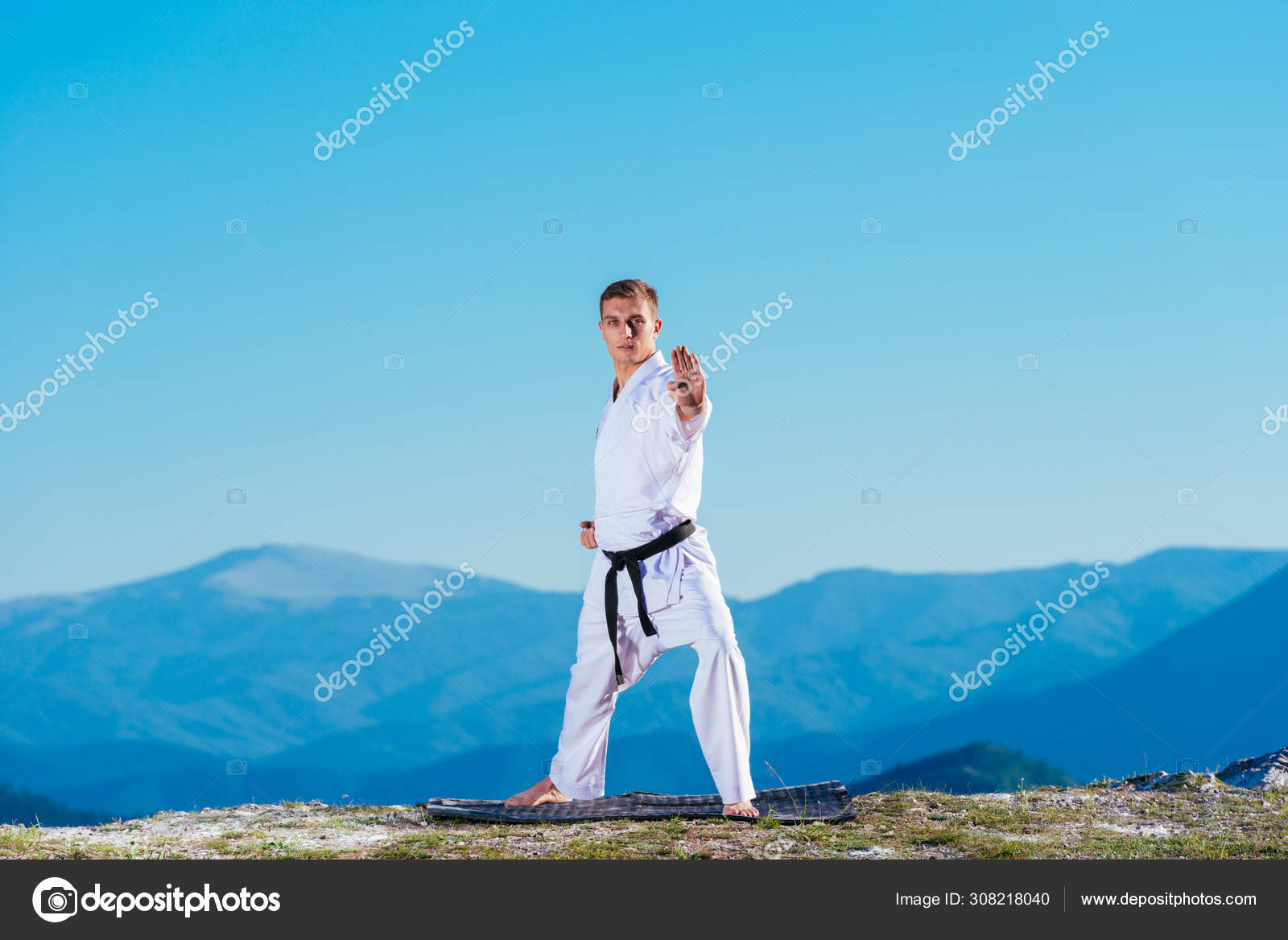 Blond karate athlete does kata on top of a mountain while perfor Stock ...