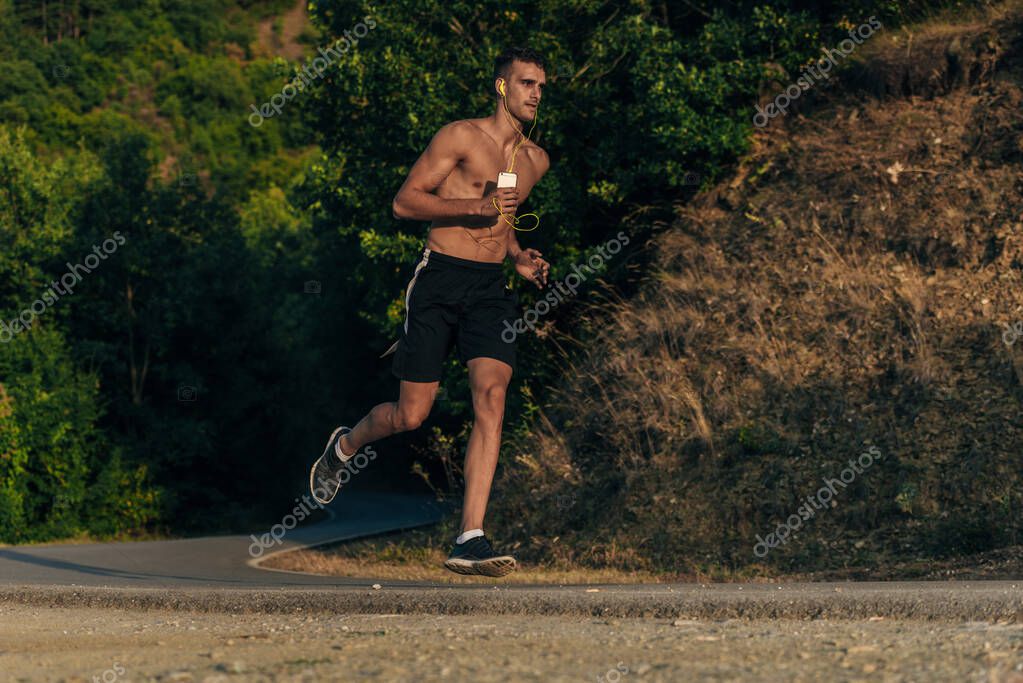 Hombre corriendo escuchar música en su dispositivo contra el cielo azul ...