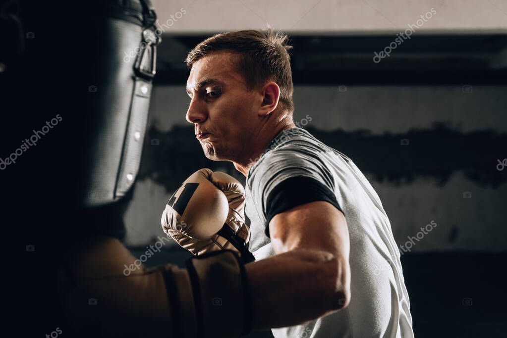 Boxeador masculino entrenando con saco de boxeo en pabellón deportivo ...