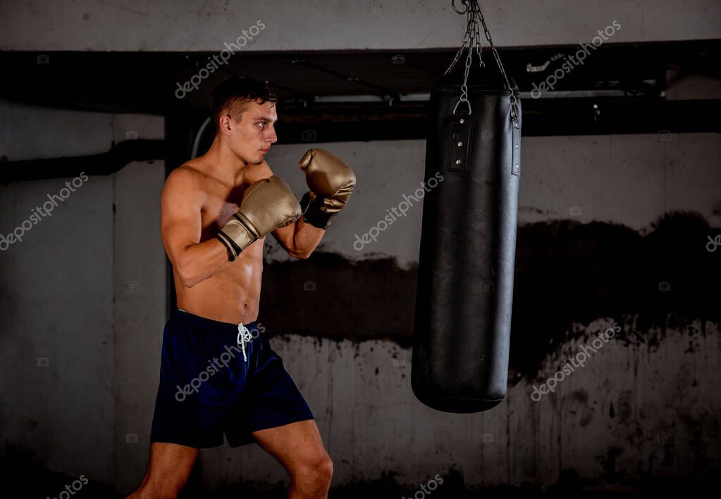 Un joven boxeador entrenando en sacos de boxeo en el gimnasio ...