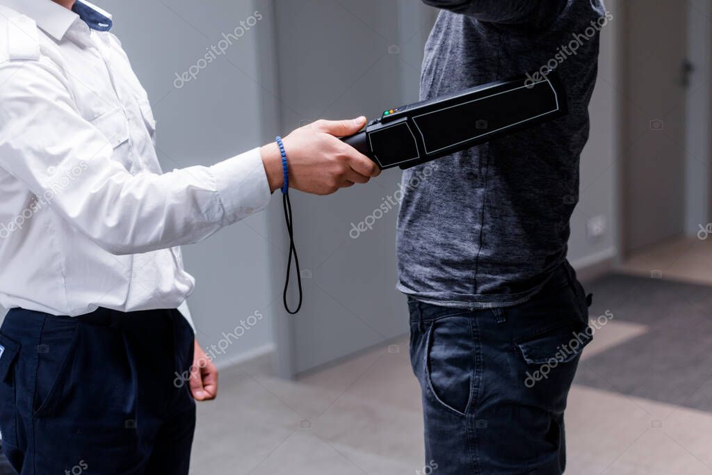 Guardia de seguridad revisando a una persona en el puesto de control de ...