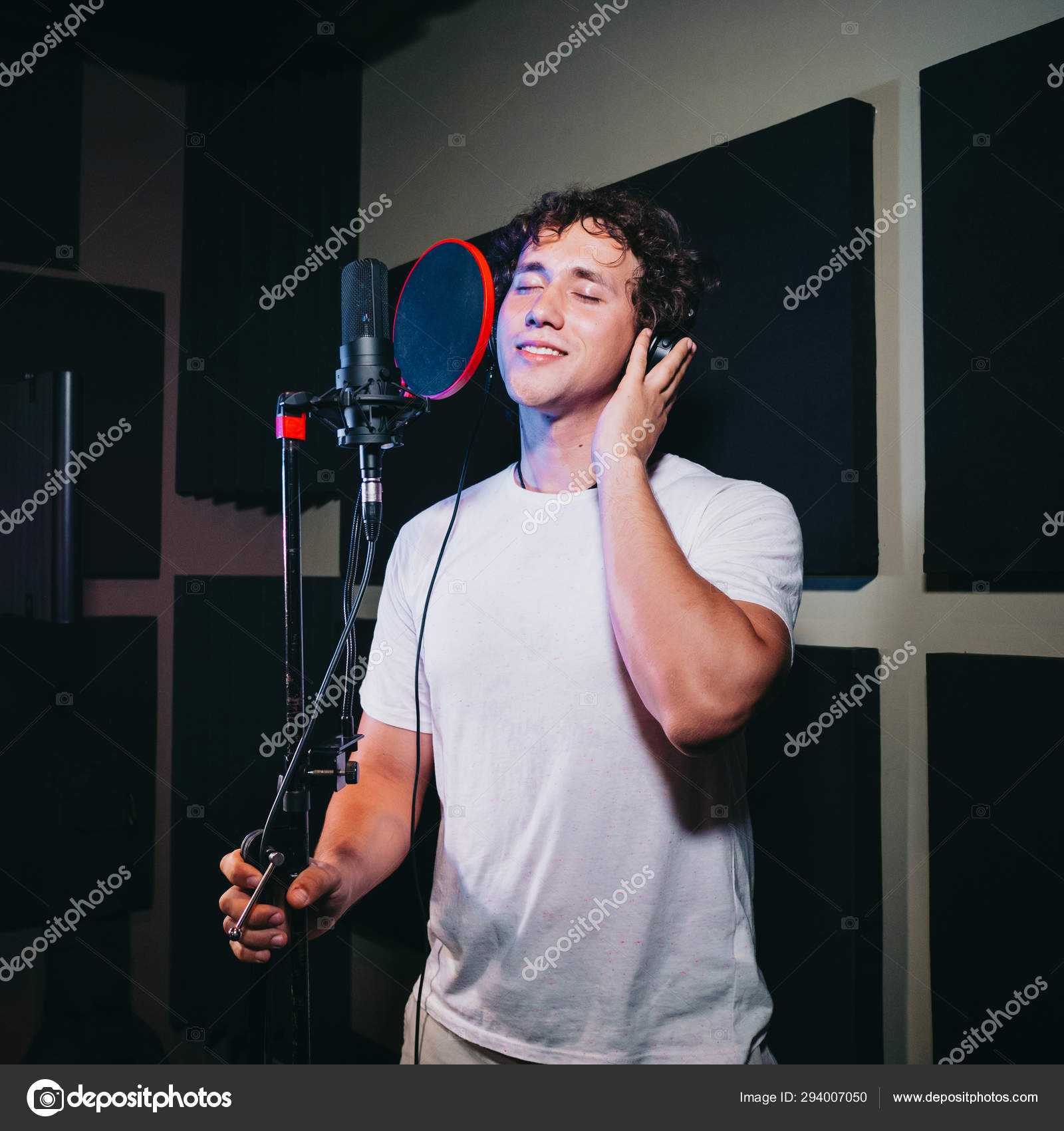 An expressive man sings a song in a microphone in a recording studio ...