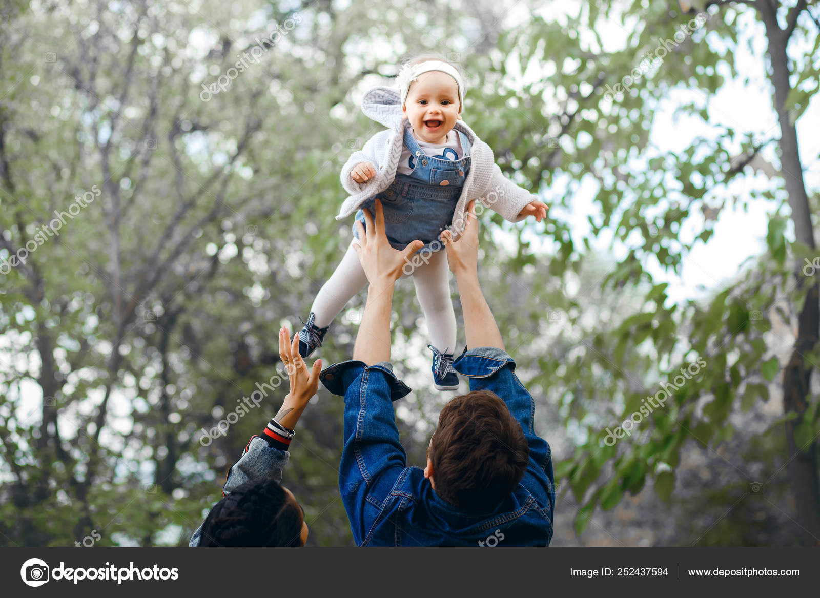 Happy family outdoors activity, father raises baby up, laughing and ...