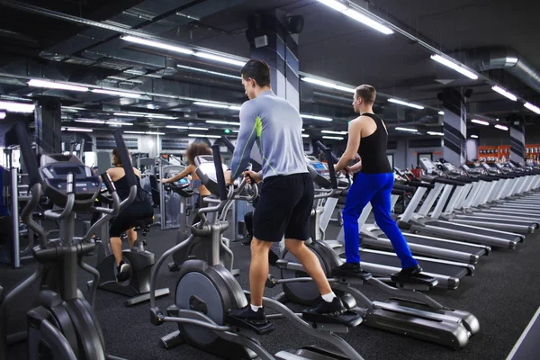 People exercising on training machines in gym - Stock Image - Everypixel