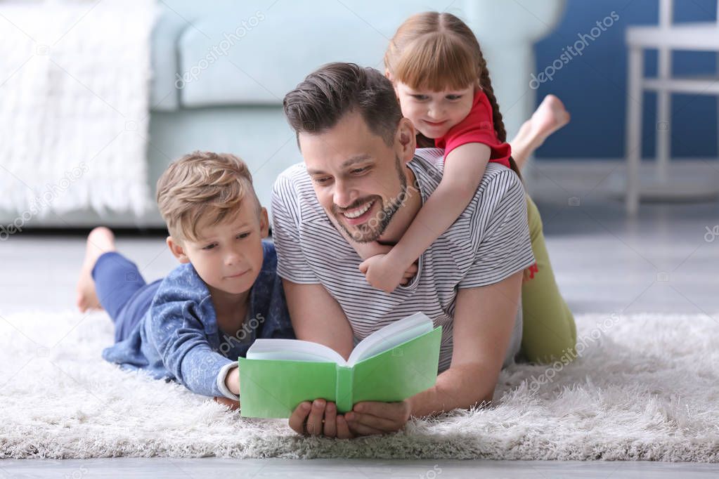 Padre y sus hijos leyendo el libro juntos en casa 2023