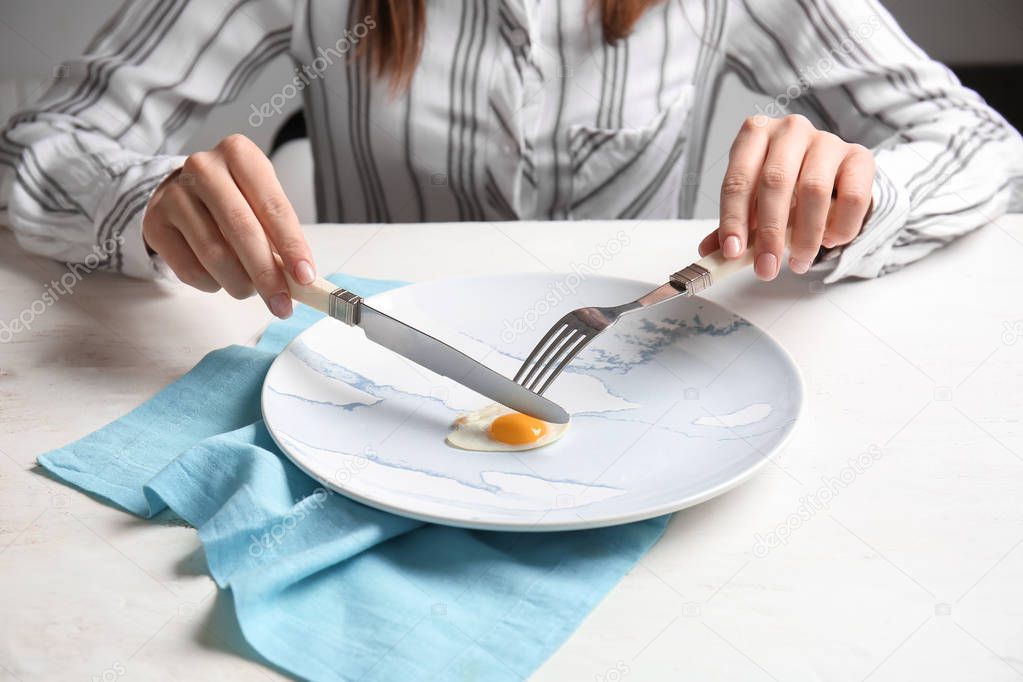 Mujer comiendo huevo de codorniz frito en la mesa 2022