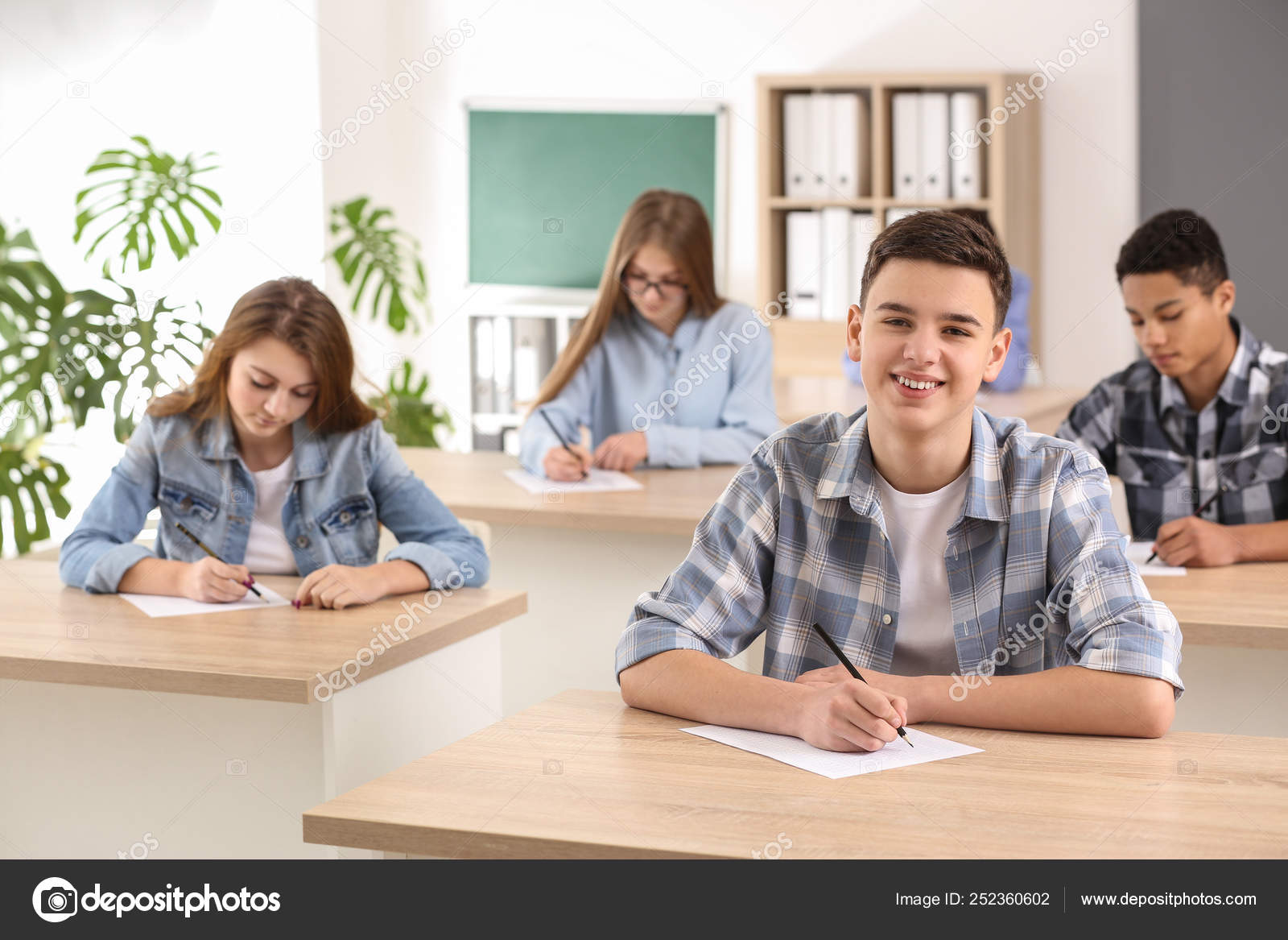 Pupils passing school test in classroom Stock Photo by ©serezniy 252360602