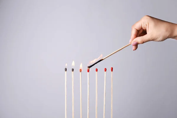 Female hand lighting matches on grey background - Stock Image - Everypixel