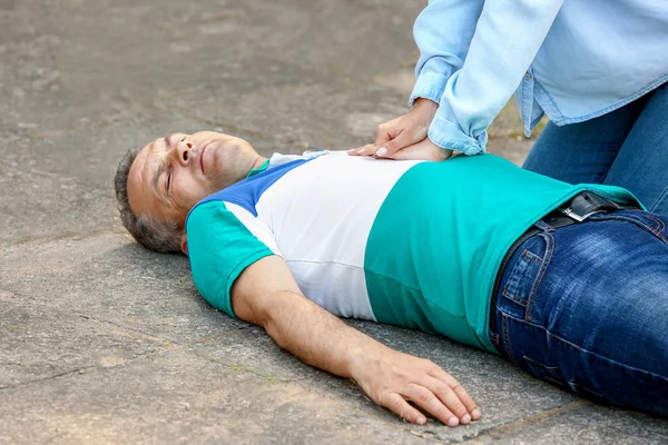 Female passer-by doing CPR on unconscious mature woman outdoors — Stock ...