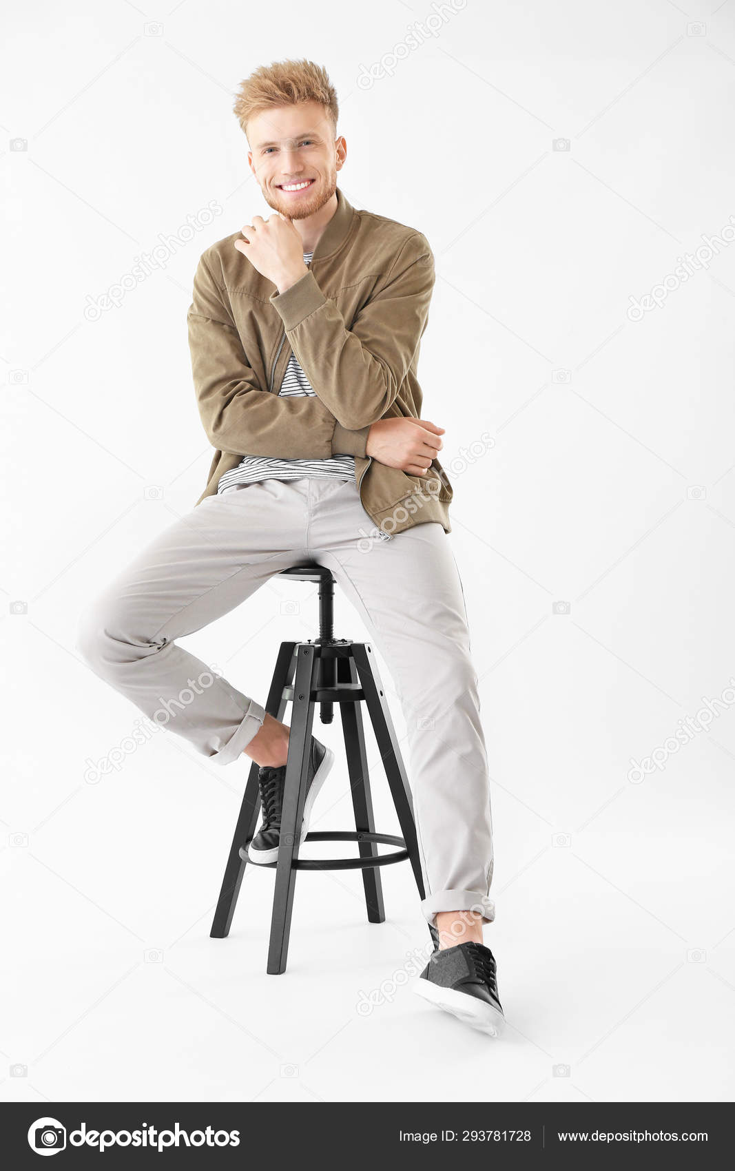 Stylish young man sitting on stool against white background — Stock ...