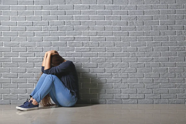 Woman having panic attack while sitting near brick wall - Stock Image ...