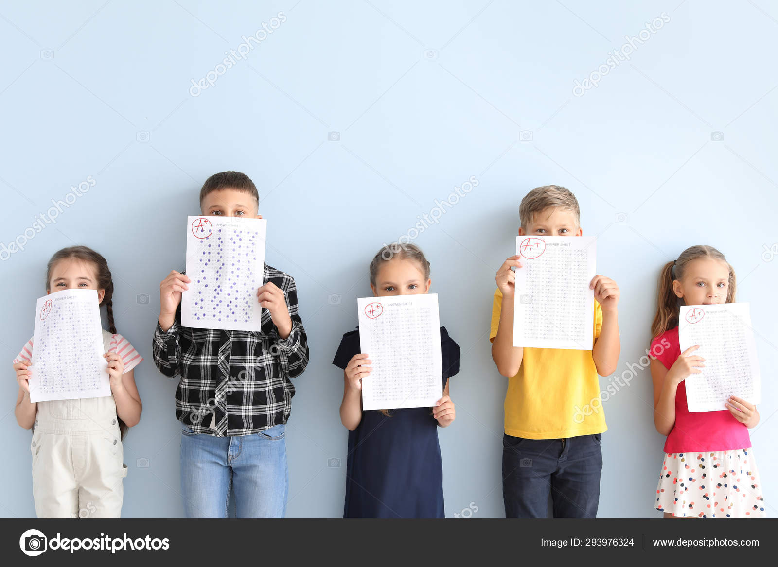 Children with answer sheets for school test on light color background ...