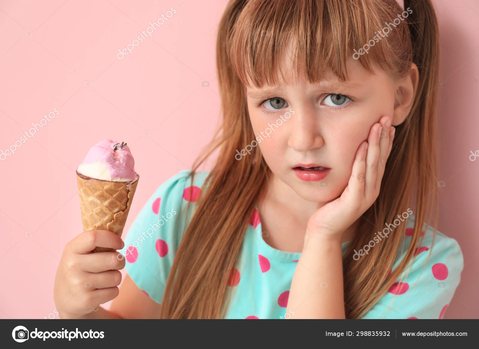Little girl with sensitive teeth and cold ice-cream on color background ...