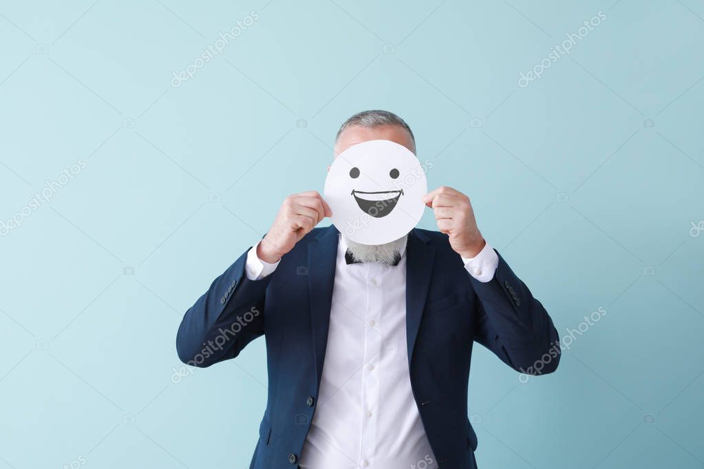 Hombre maduro escondiendo la cara detrás de emoticonos en el fondo de ...