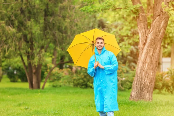 Young man with umbrella wearing raincoat outdoors - Stock Image ...