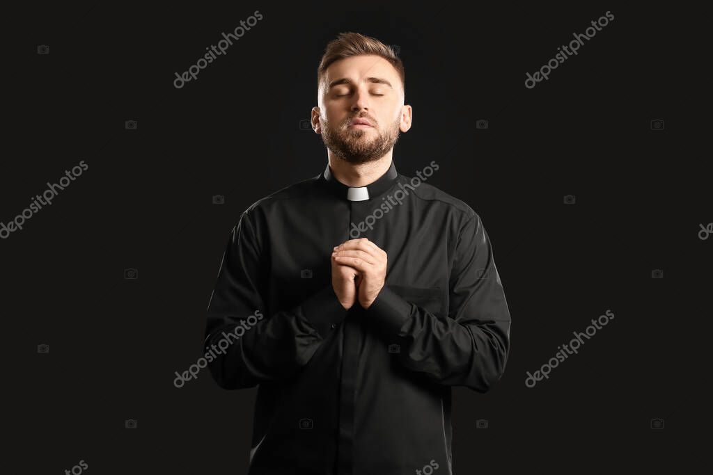 Joven sacerdote rezando a Dios sobre fondo oscuro 2022
