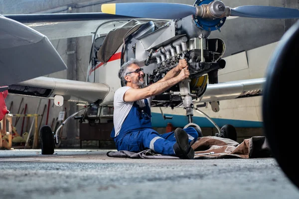 Aircraft mechanic repairs an aircraft engine in an airport hangar ...