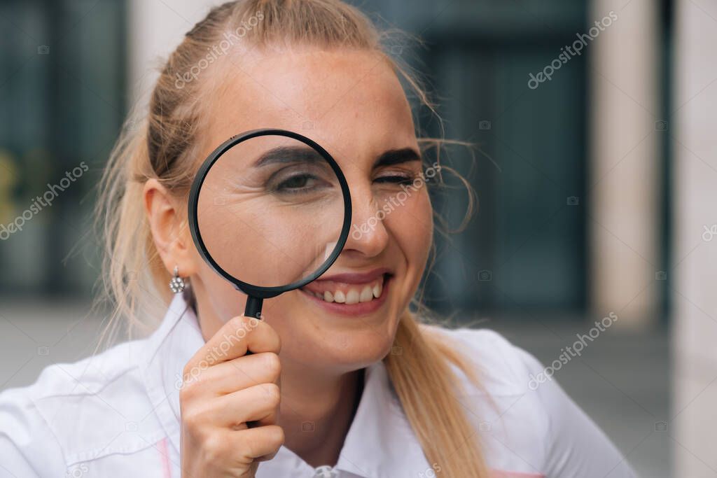 Una doctora vestida con una bata blanca mira a través de una lupa. El ...