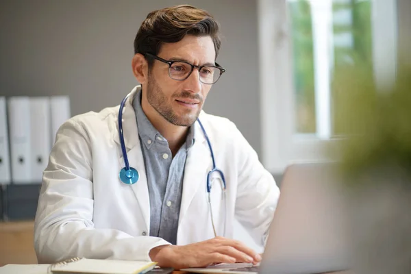 Handsome doctor in lab coat at office - Stock Image - Everypixel