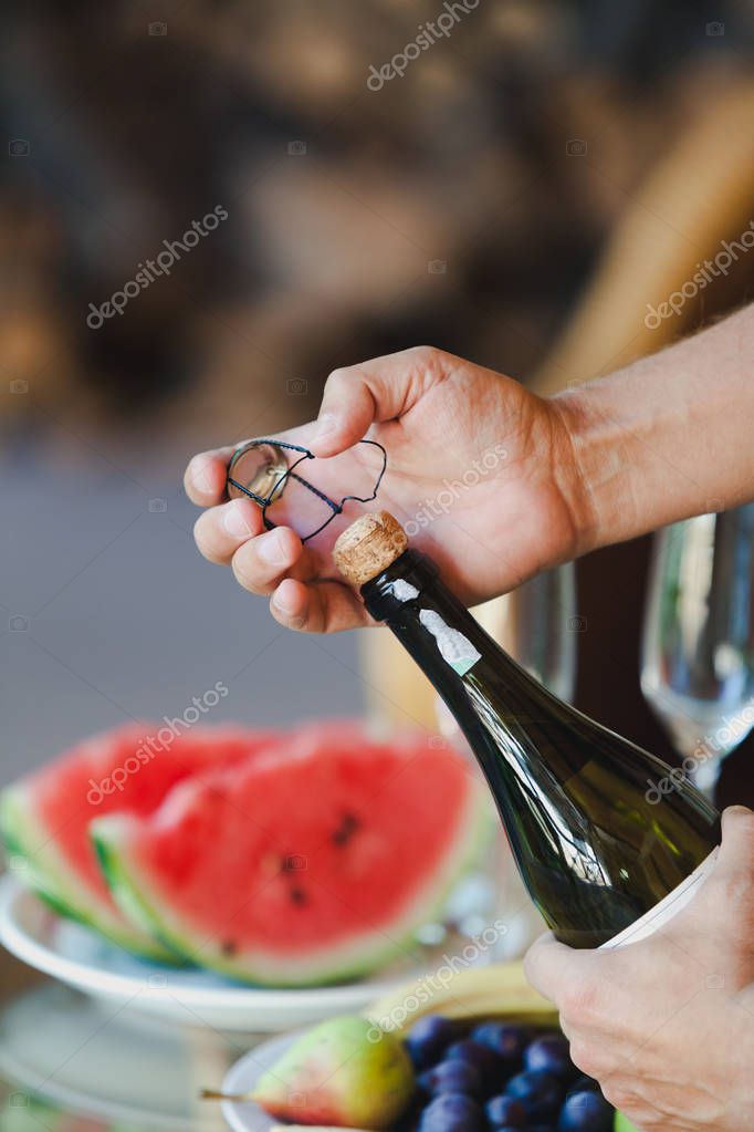 Las manos sacan la musa de un corcho en una botella de vino espumoso ...