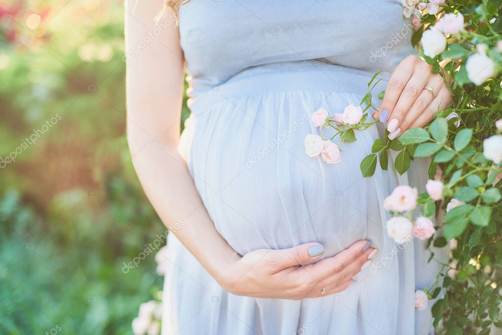 Vista cercana de la joven modelo embarazada abrazando el vientre ...