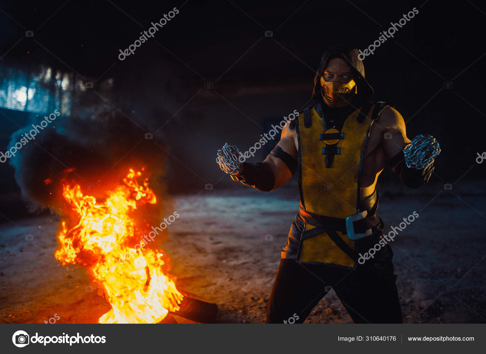 Man portraying warrior Scorpion with chains poses at fire backgr ...