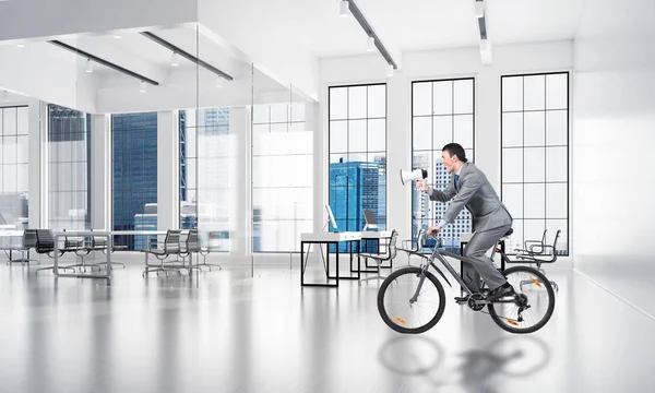 Manager in business suit riding bicycle at conference hall. Businessman ...