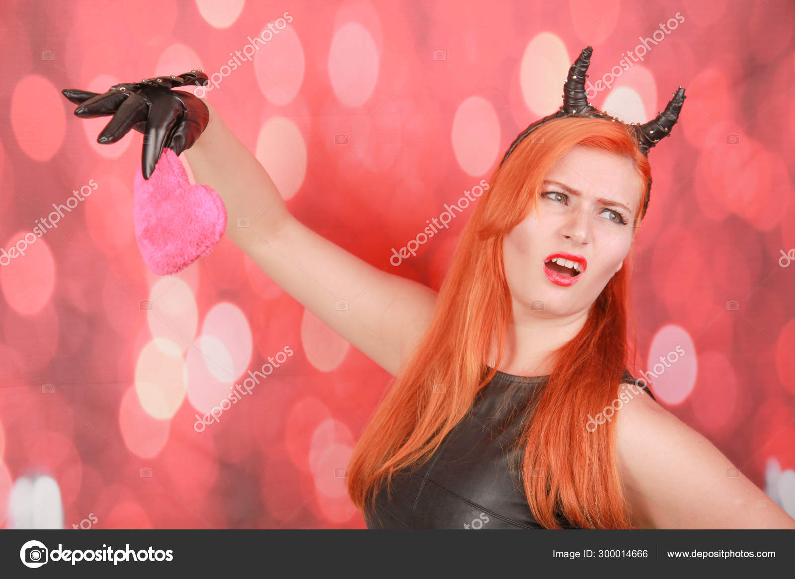 Devil girl with pink plush toy with heart shape on red background Stock ...